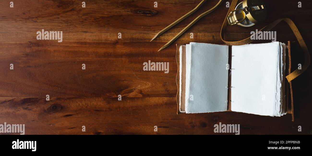 Vintage leather journal or diary on a black table with a compass next ...