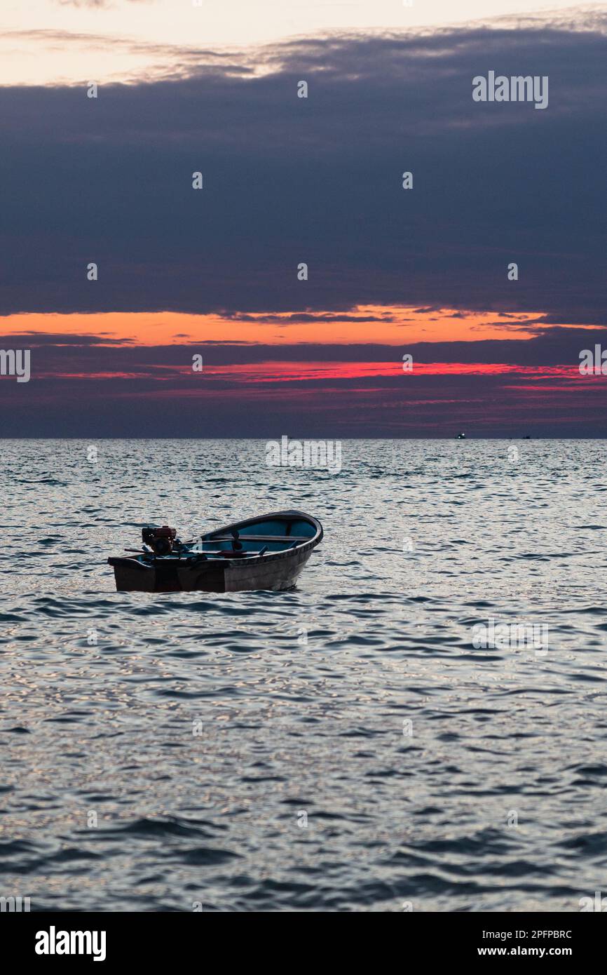 A tranquil seascape at sunset, featuring an idyllic sailboat floating ...