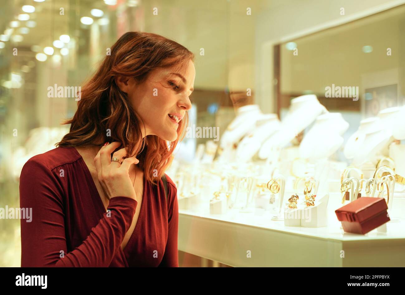 Pretty woman looking at jewelry in store window. Customer near ...