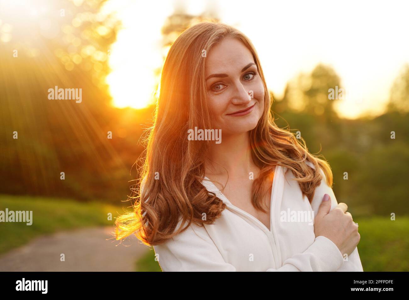 Cute blonde girl on background of sun. Ordinary happy woman enjoying ...