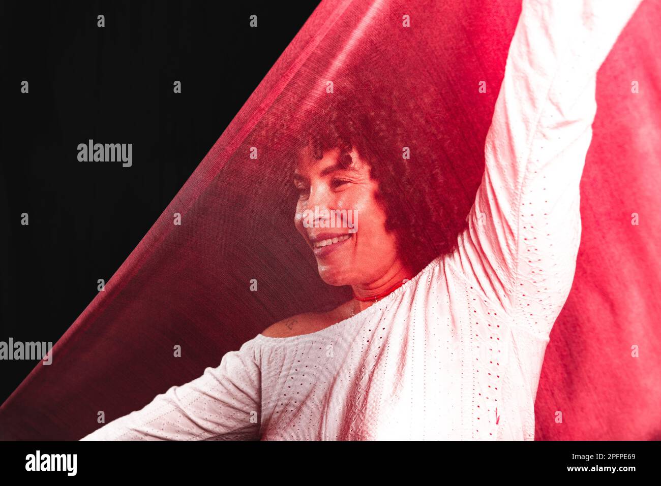 Portrait of a woman with red cloth stretched in front of her face ...