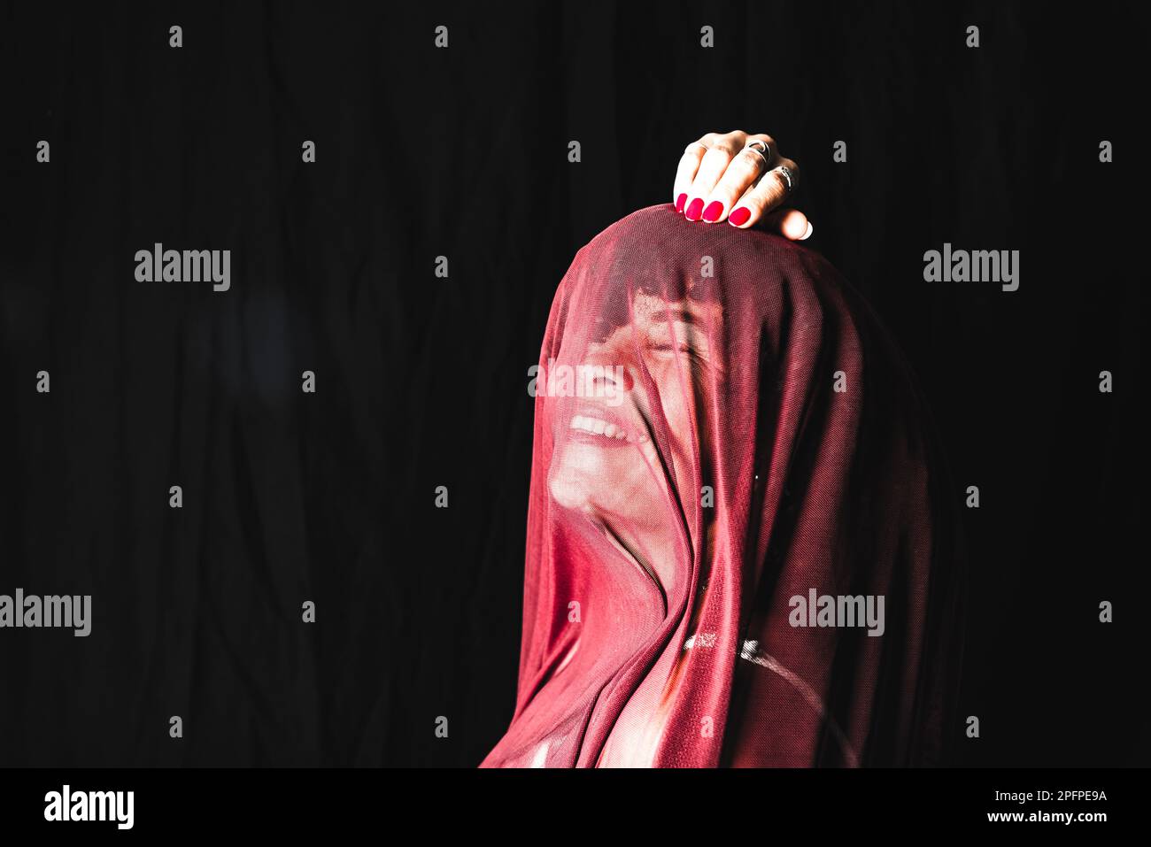 Beautiful woman with red cloth over her head making hand gestures ...