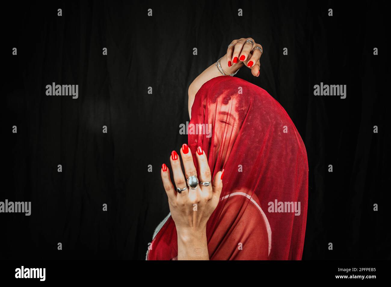 Beautiful woman with red cloth over her head making hand gestures ...