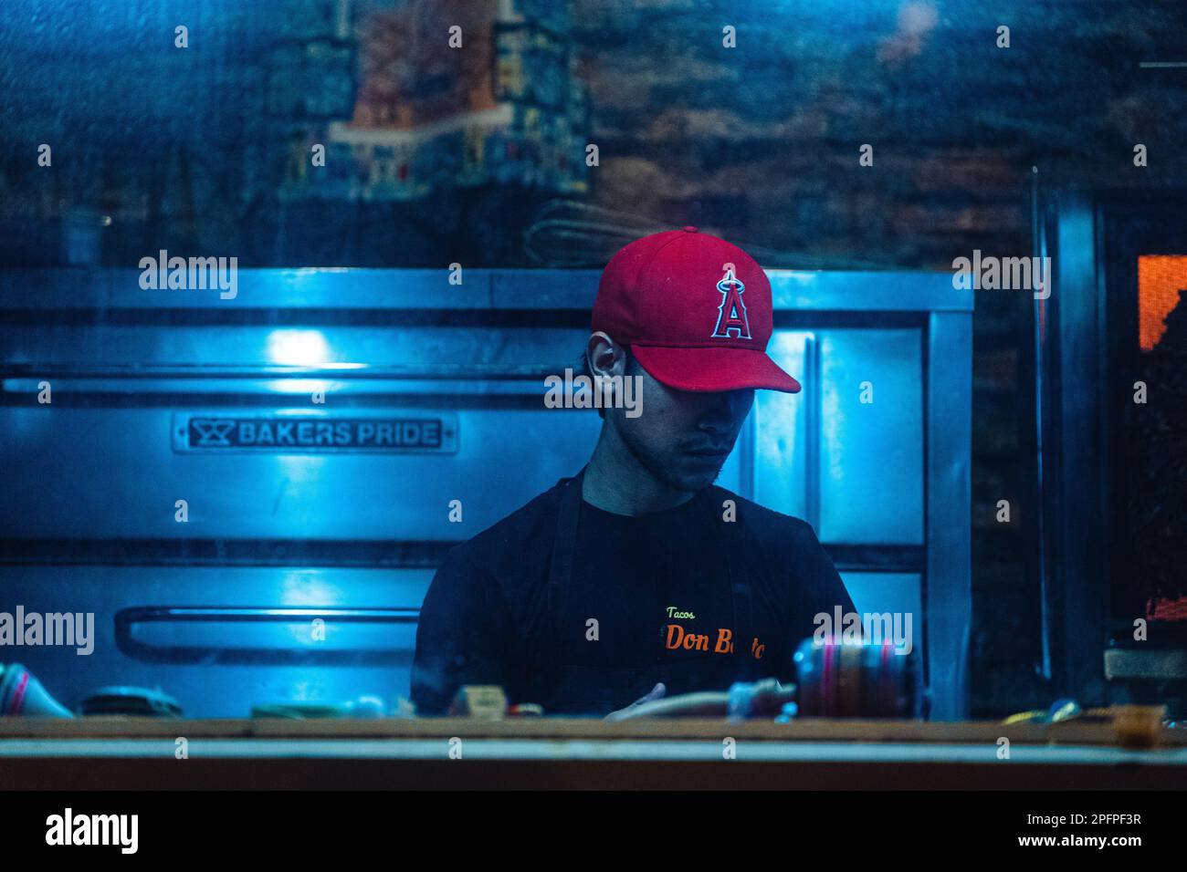 A man wearing a red baseball cap working in a diner at night Stock ...