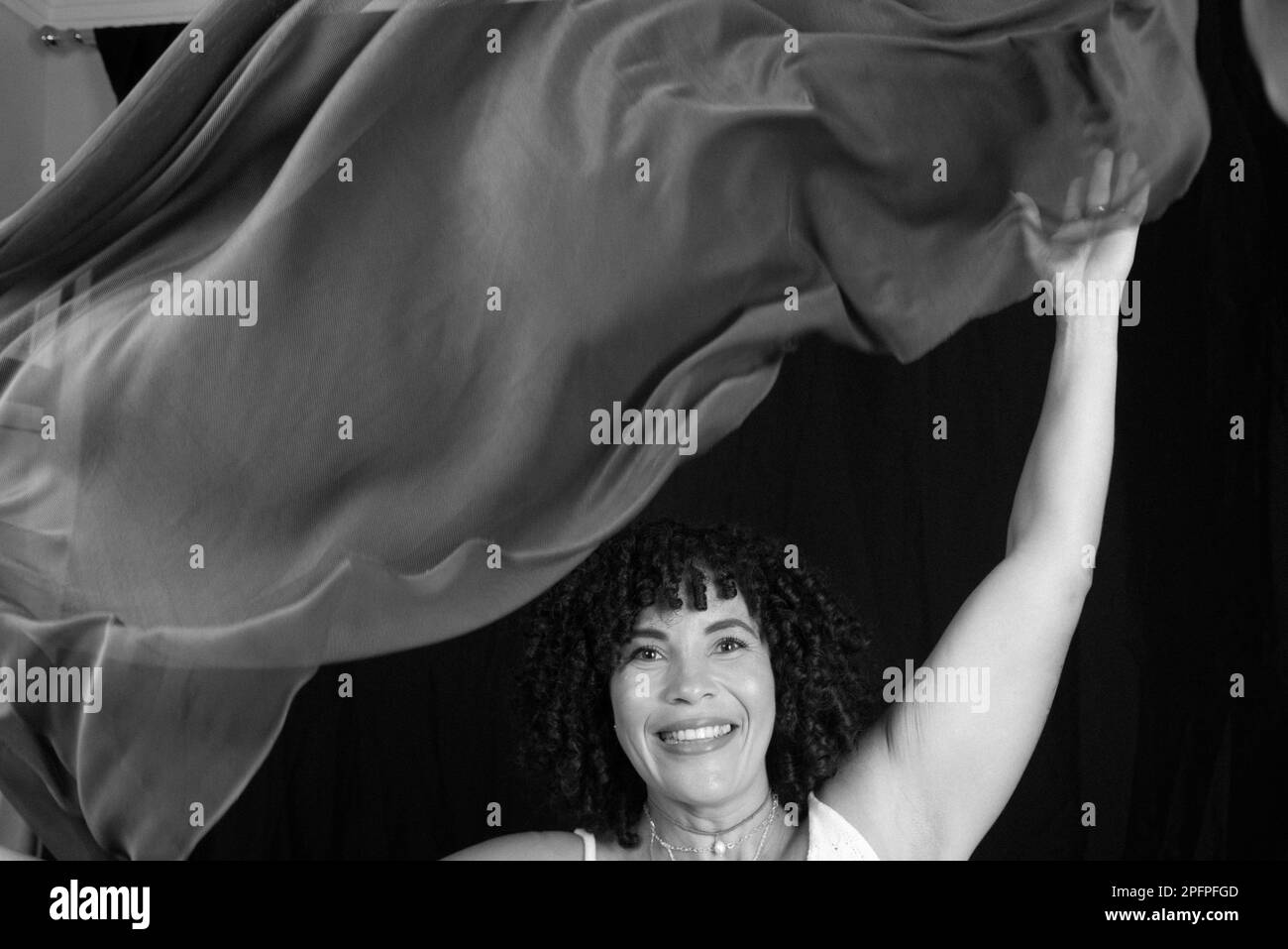 Black and white portrait of woman throwing cloth in the air. Isolated ...