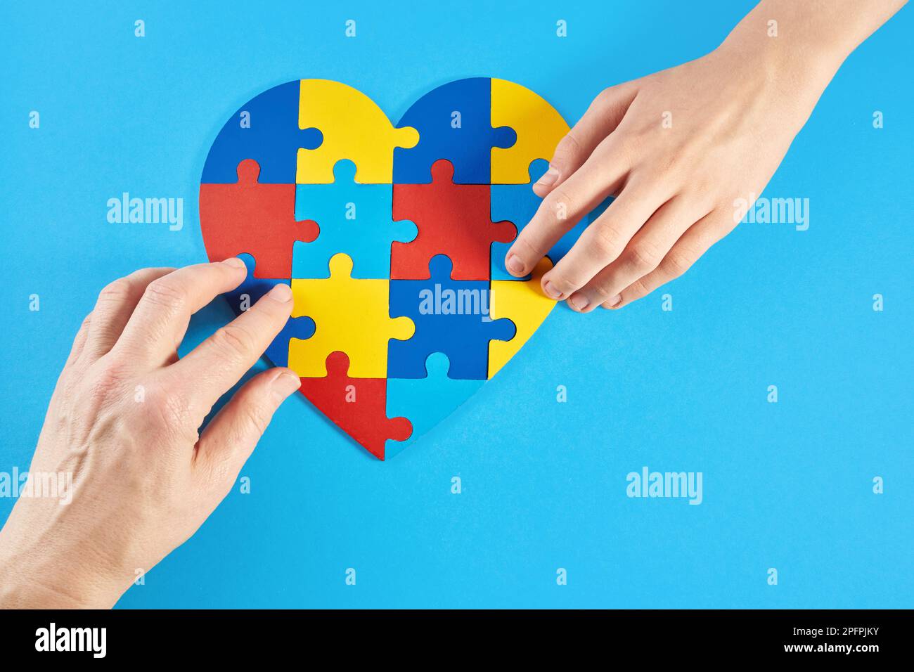 Father and autistic son hands holding jigsaw puzzle heart shape. Autism ...