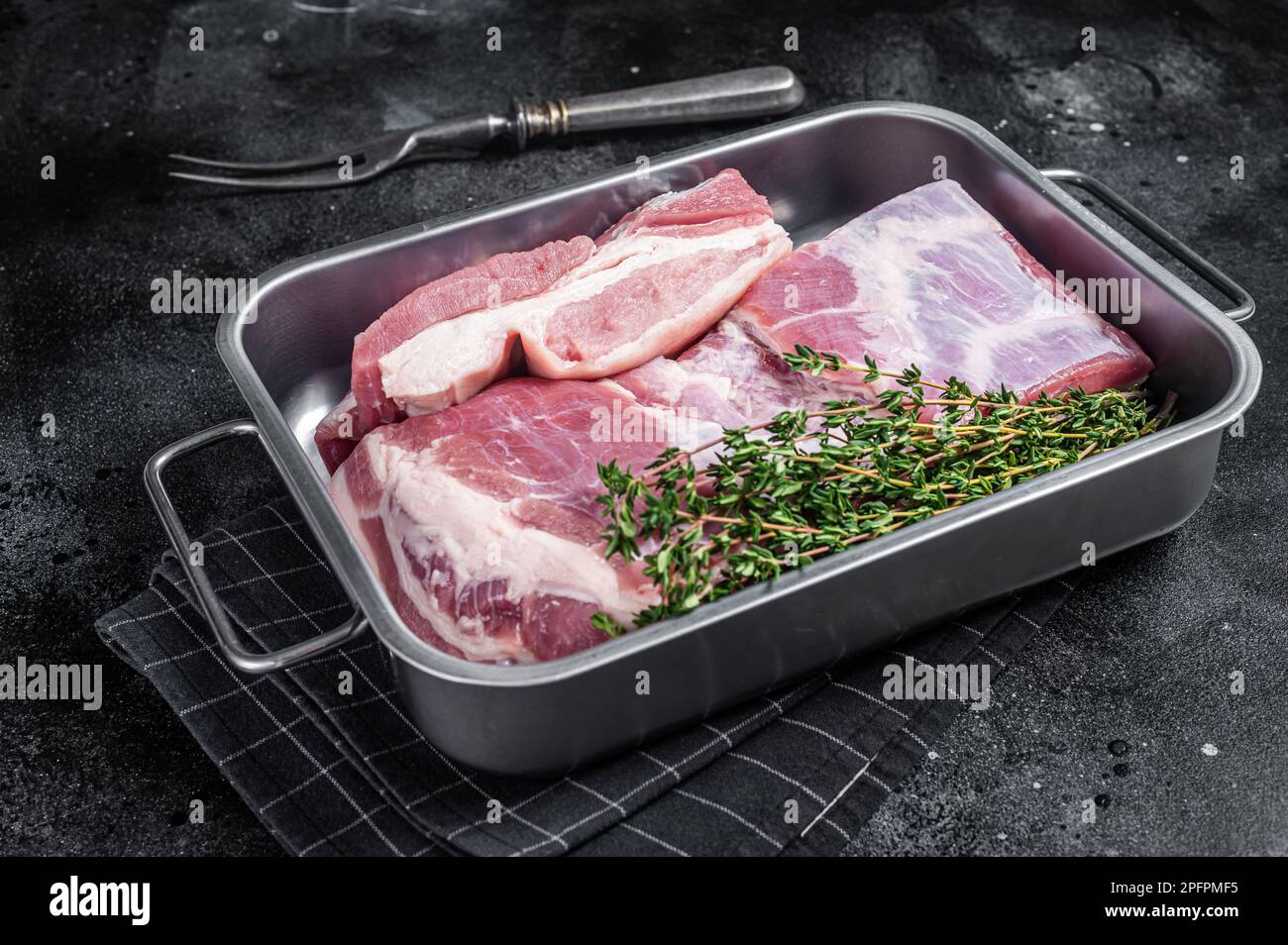 Fresh Raw pork belly with skin in a steel tray with herbs. Black ...