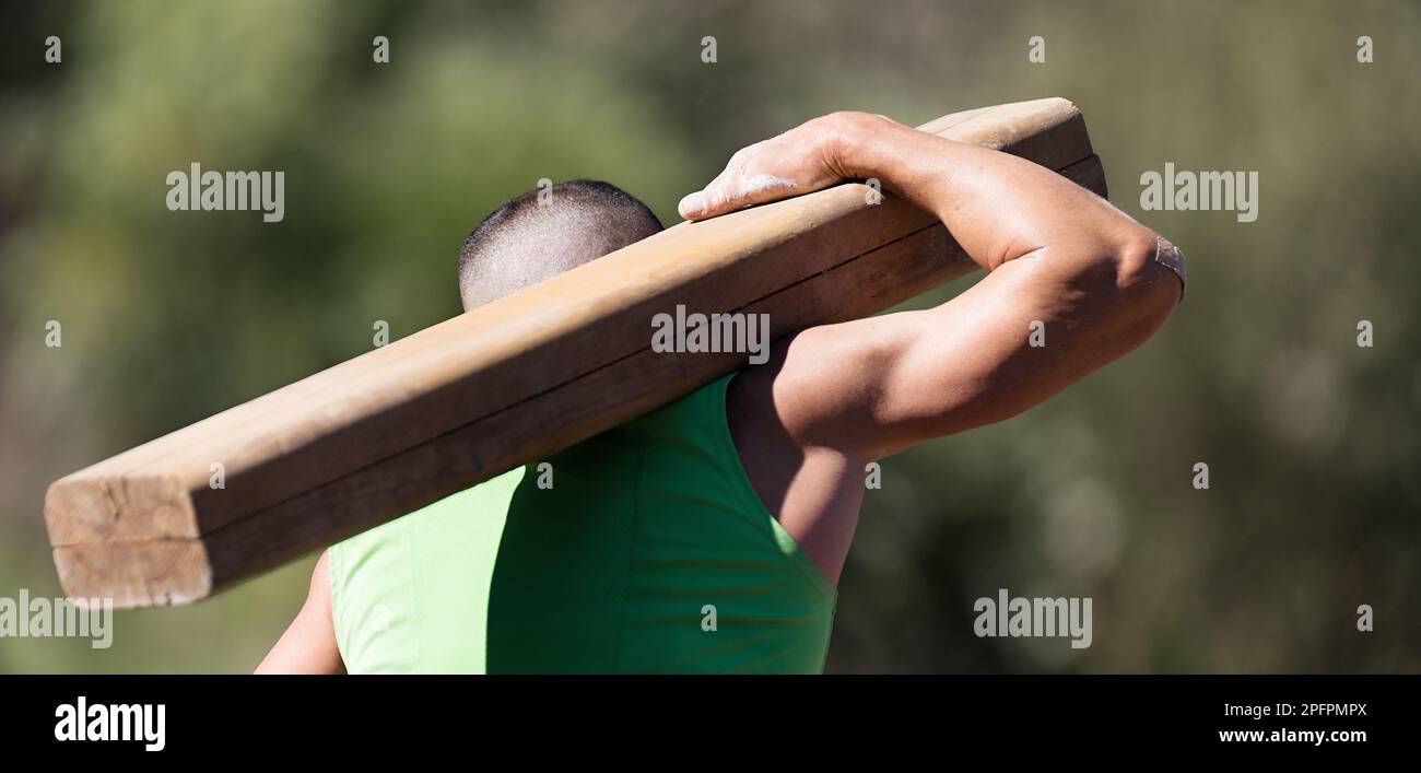 Man carrying wooden log in a test of the race. Mud race runners ...