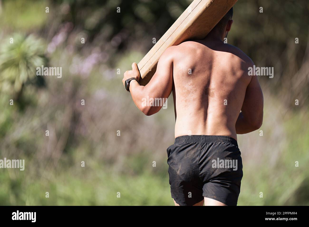 Man carrying wooden log in a test of the race. Mud race runners ...
