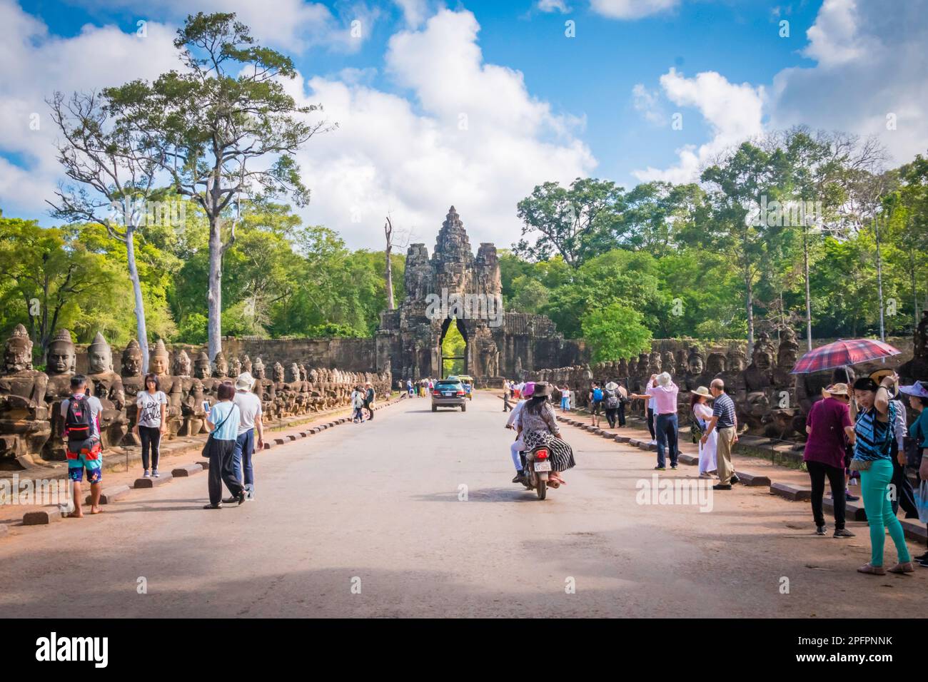 Road leading to a temple with tourists walking in Angkor Wat in ...