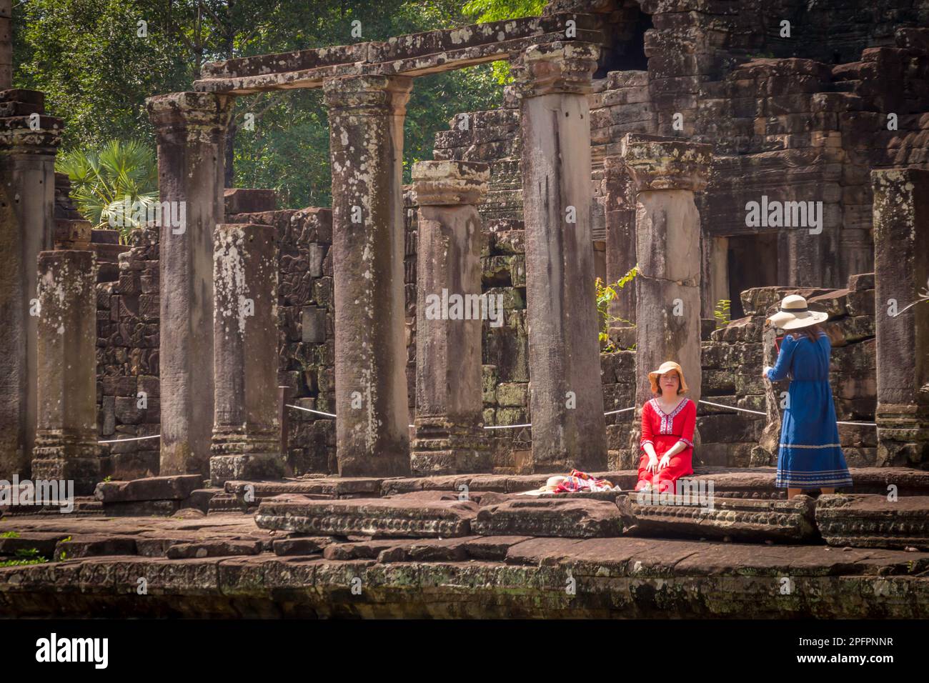 Tourists ladies in red and blue dress are taking photos at a photo session in Angkor Wat in ...