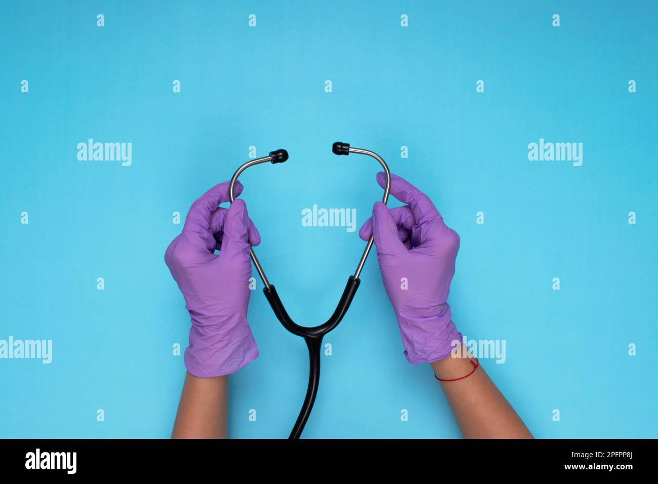 hands holding stethoscope with lilac colored medical gloves on light ...