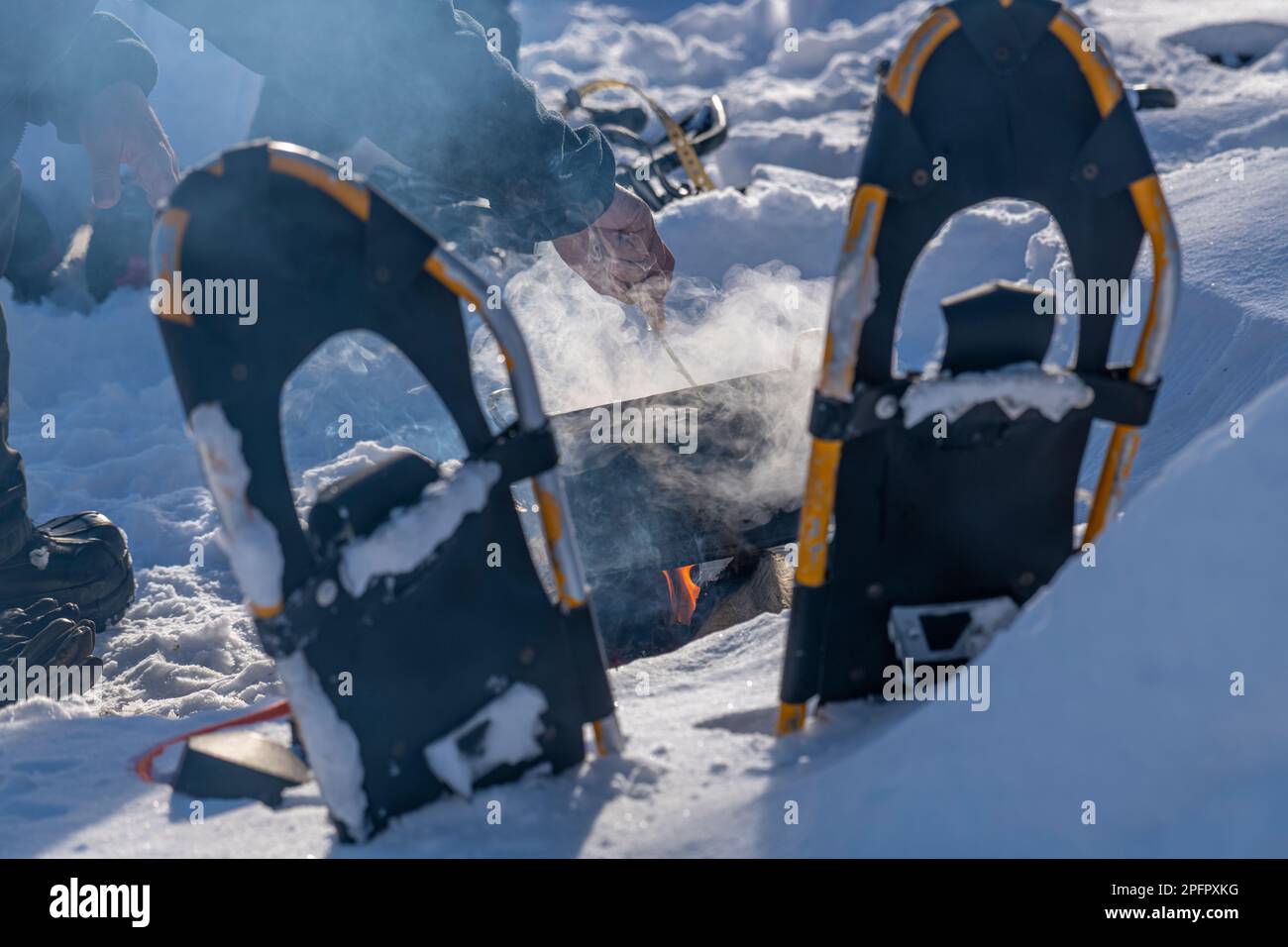 Snow shoes in the snow whilst a pot of fish stew simmers on an open ...