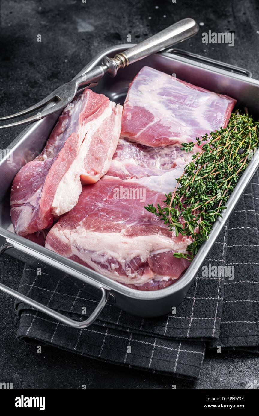 Fresh Raw pork belly with skin in a steel tray with herbs. Black ...