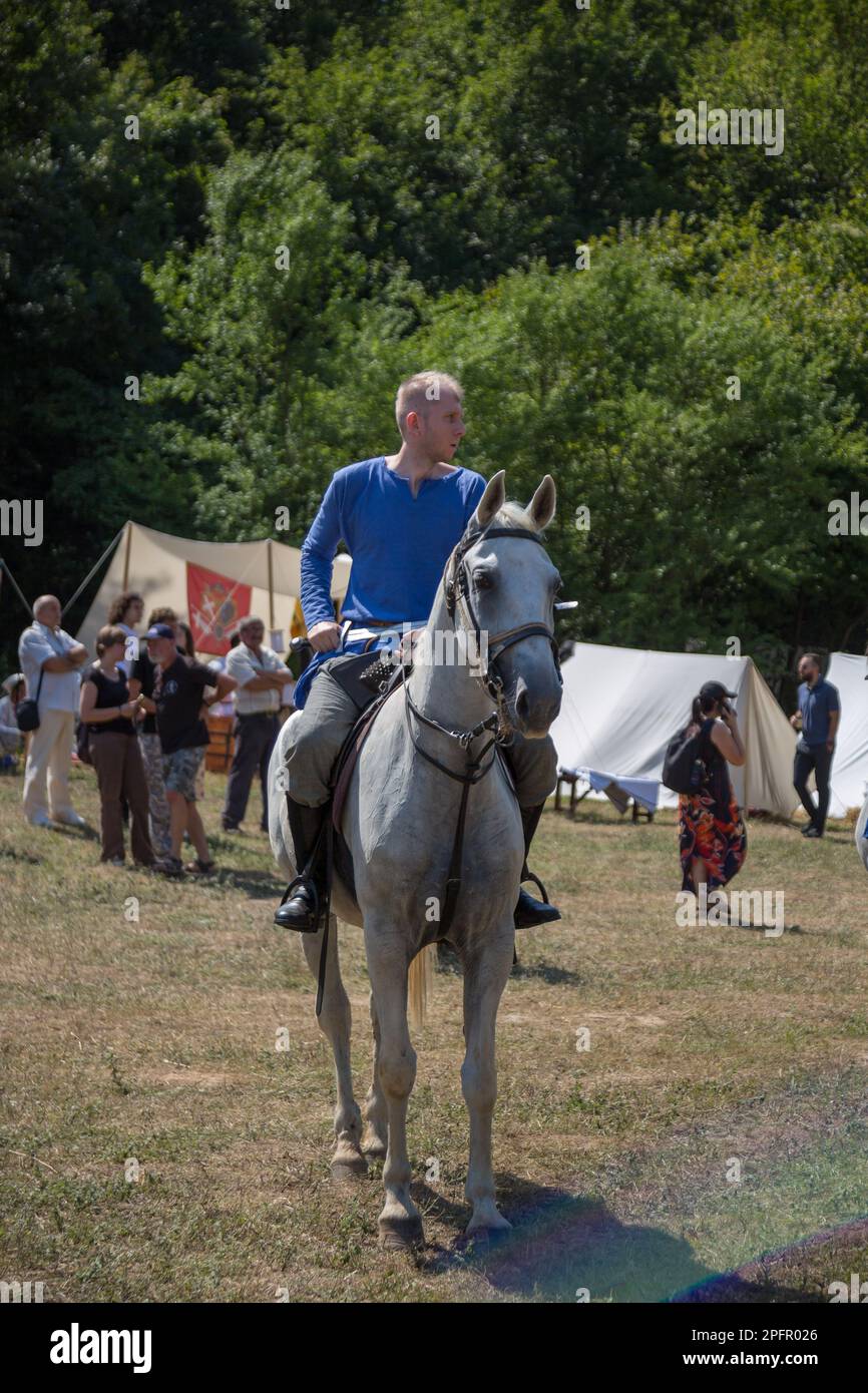 A man in a blue shirt sit on a horse and carry a sword Stock Photo - Alamy