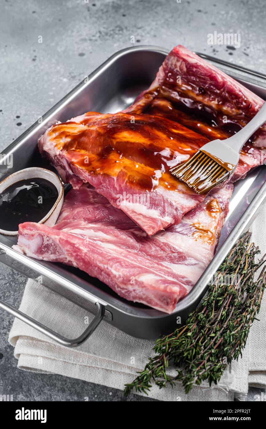 Cooking of Raw pork spare ribs with barbecue sauce. Gray background ...