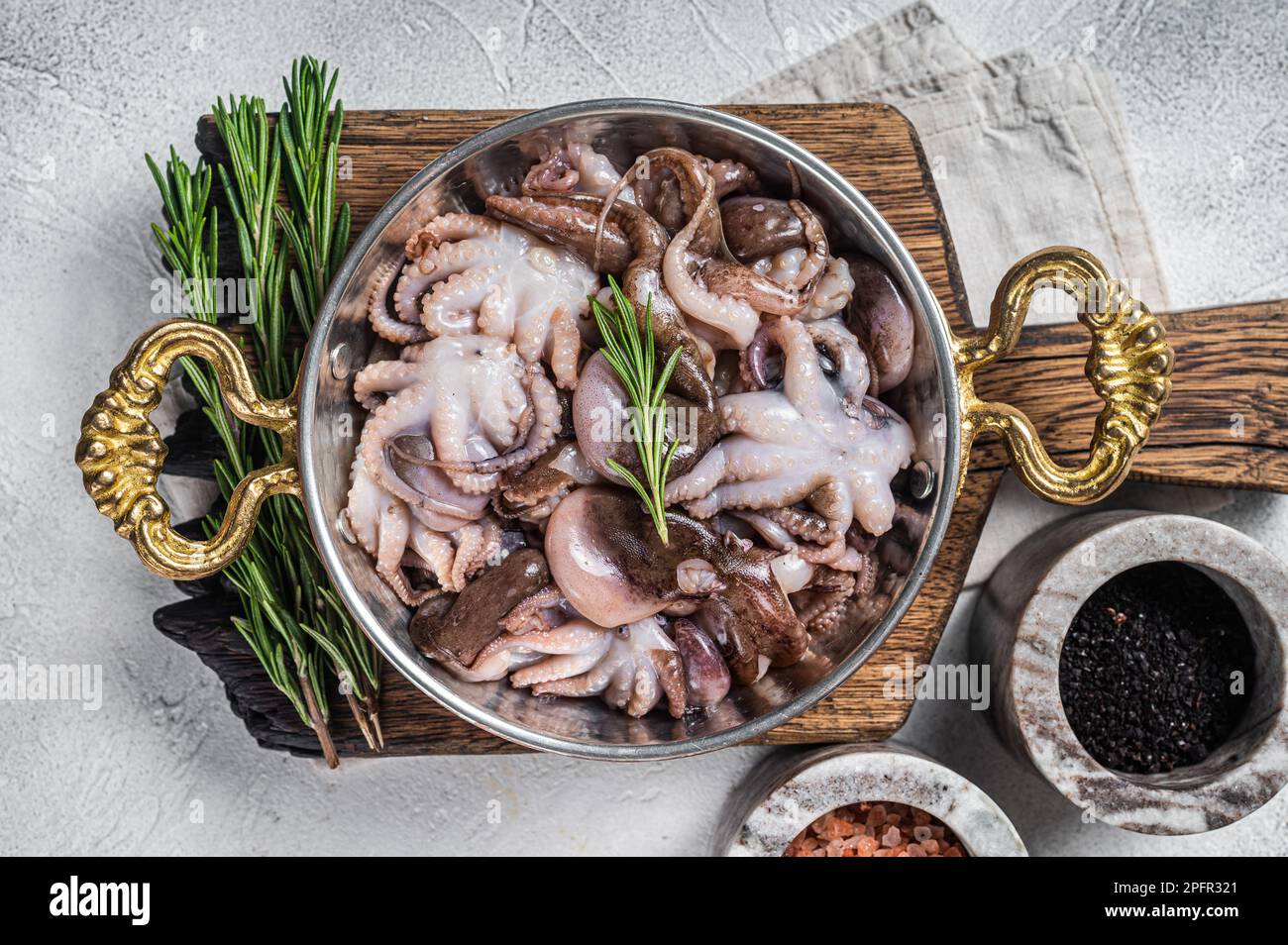 Ready for cooking raw mini baby octopus in a skillet. White background ...