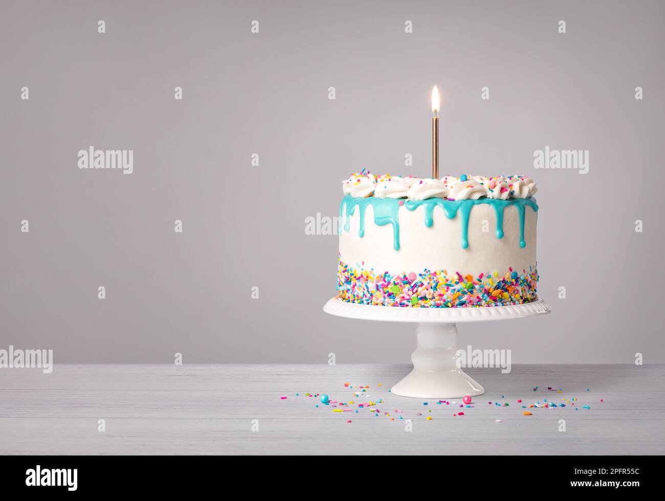 Vanilla buttercream birthday cake with a teal blue ganache drip, lit ...