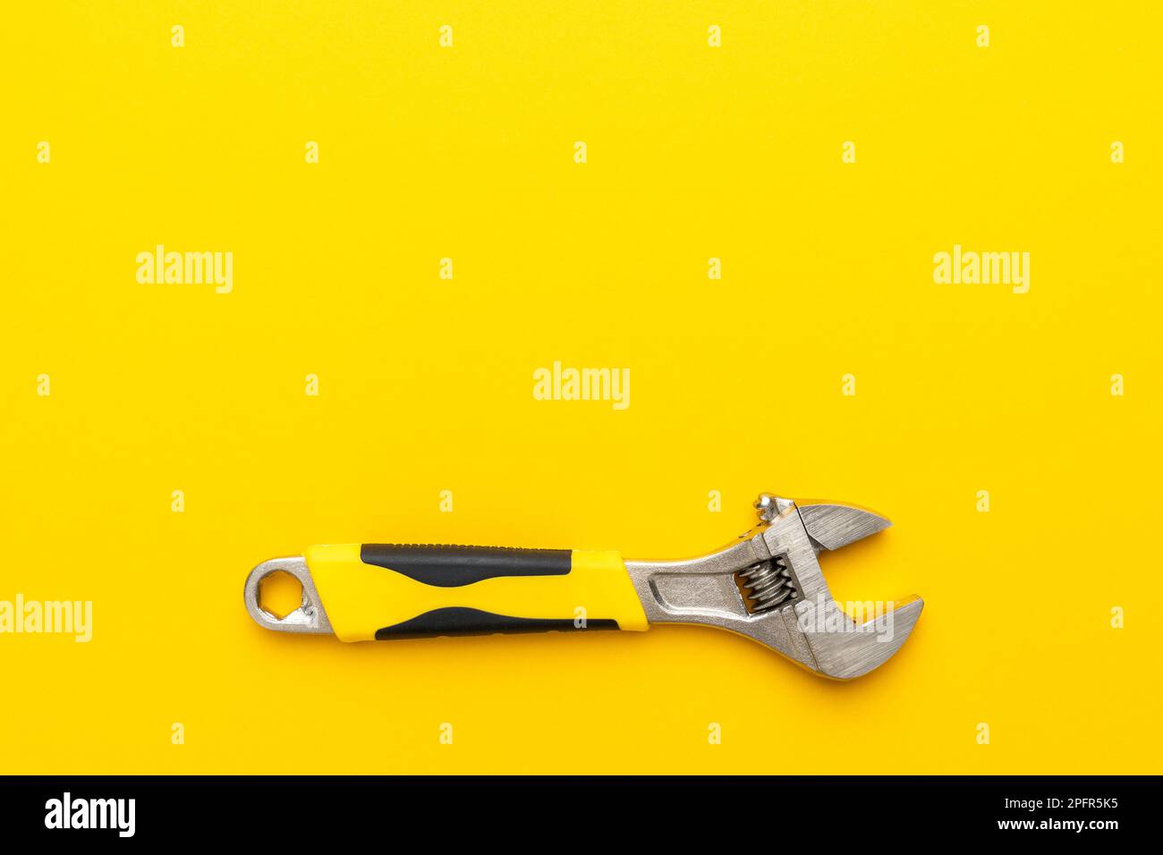 adjustable wrench with yellow handle on the yellow background ...