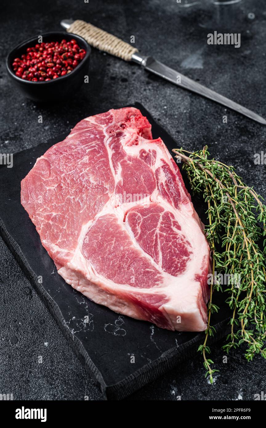 Pork neck steak from raw meat on marble board with herbs. Black ...