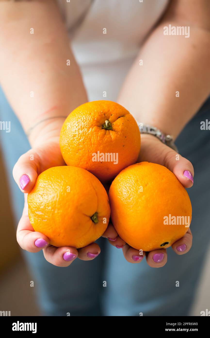 Woman holding three orange fruits in hands Stock Photo - Alamy