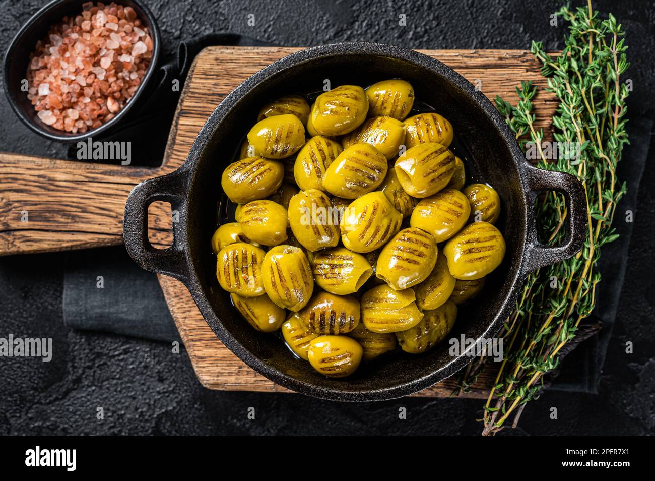 BBQ Grilled olives with garlic, olive oil and spices. Black background ...