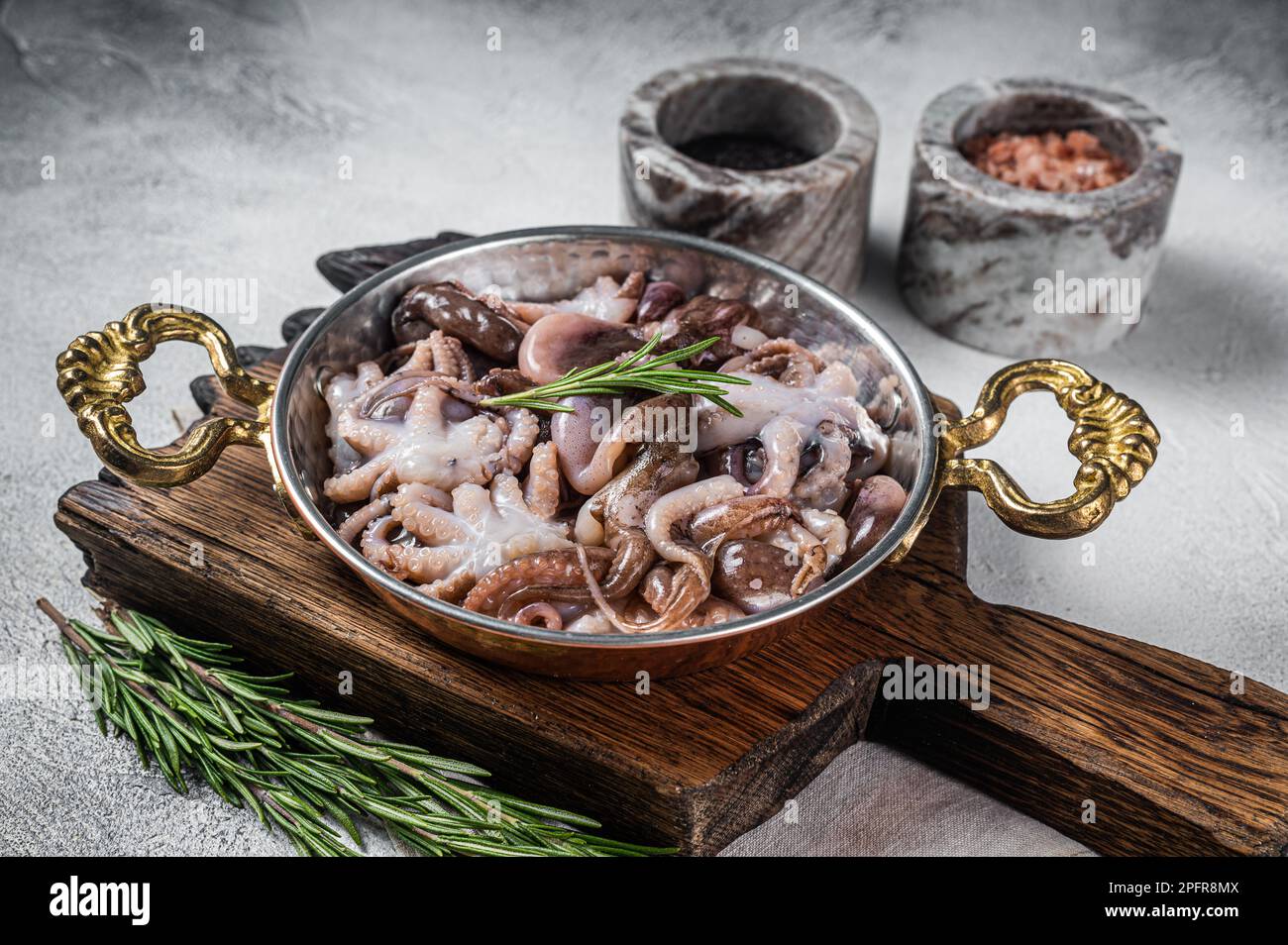 Ready for cooking raw mini baby octopus in a skillet. White background ...