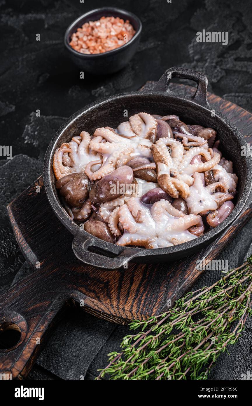 Raw young baby octopus in a skillet ready for cooking. Black background ...