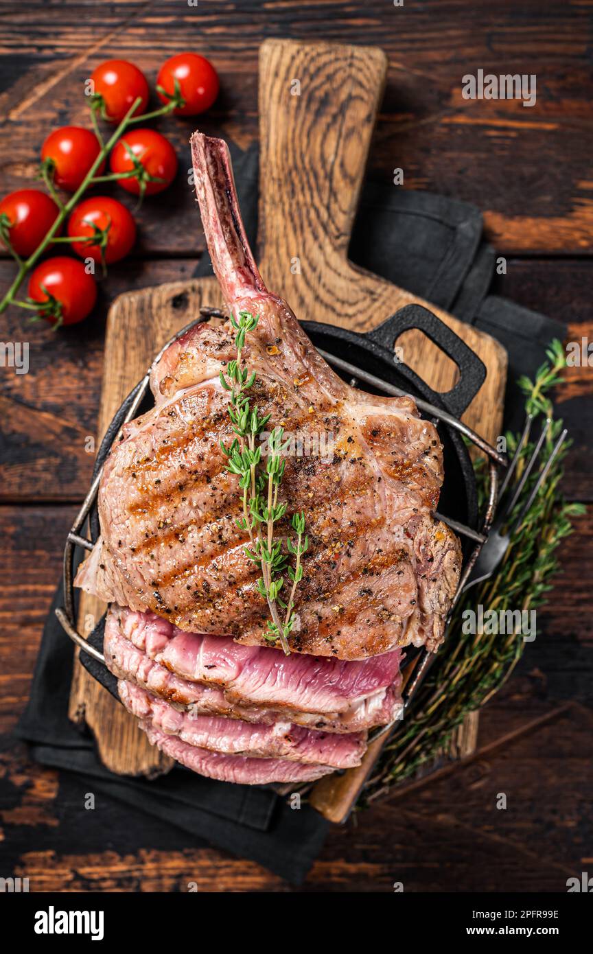 Grilled Tomahawk rib eye steak on grill with herbs. Wooden background ...