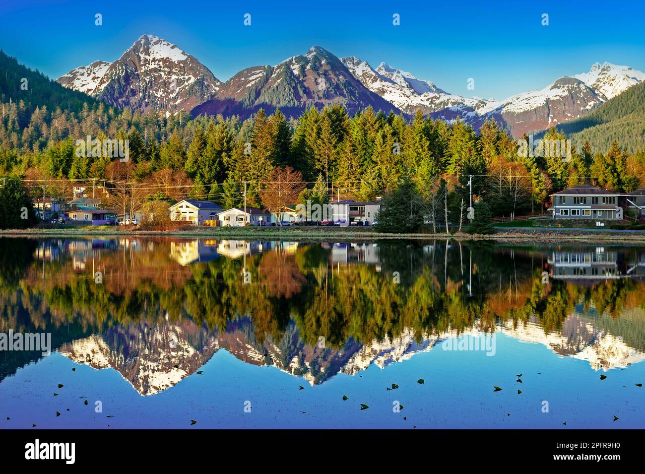 Houses and mountains reflected in the waters of Swan Lake in the early ...