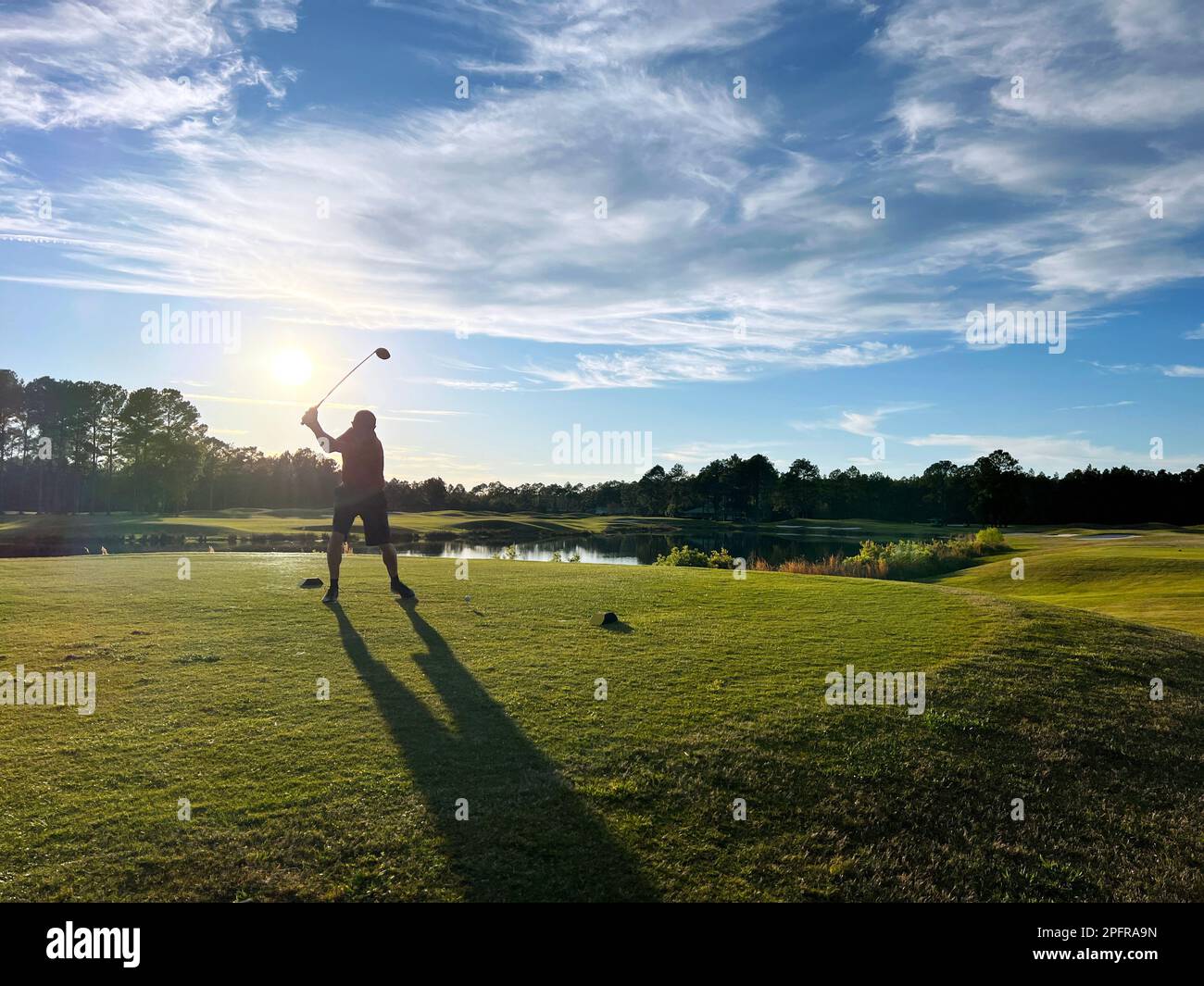 An active senior tees off around sunset on a Georgia state park golf ...