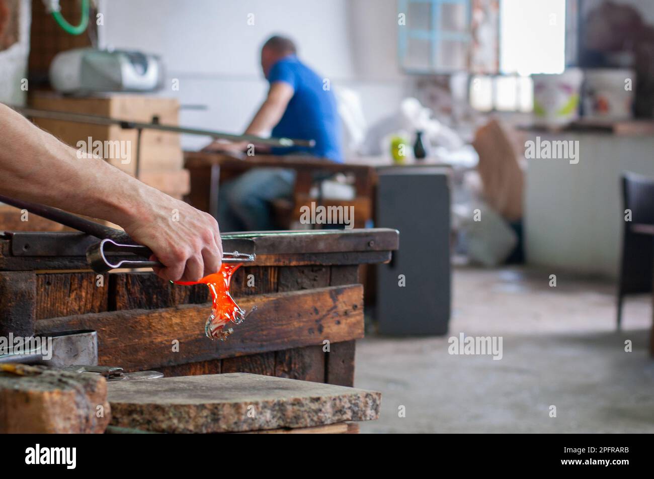 Traditional glassblowing worker shaping liquid glass. The Details and ...