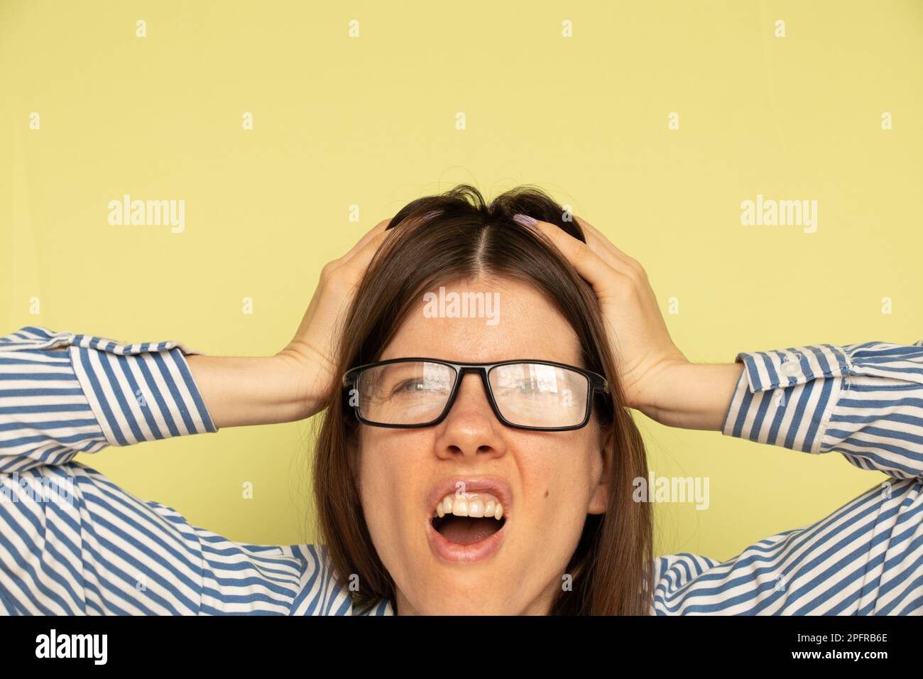 Portrait of a girl screaming who is thinking on a yellow background ...
