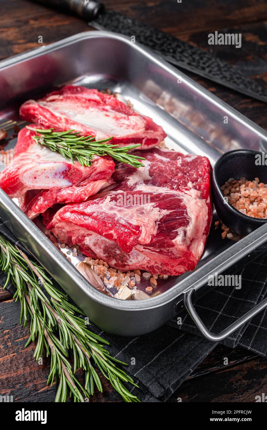 Raw beef Short Ribs in steel tray with rosemary. Wooden background. Top ...