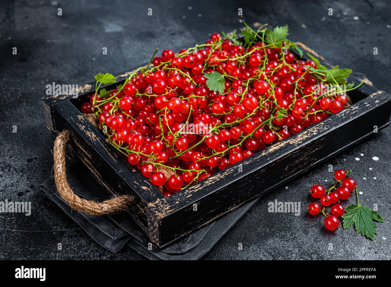 Organic Red currant berries in a wooden box. Black background. Top view ...