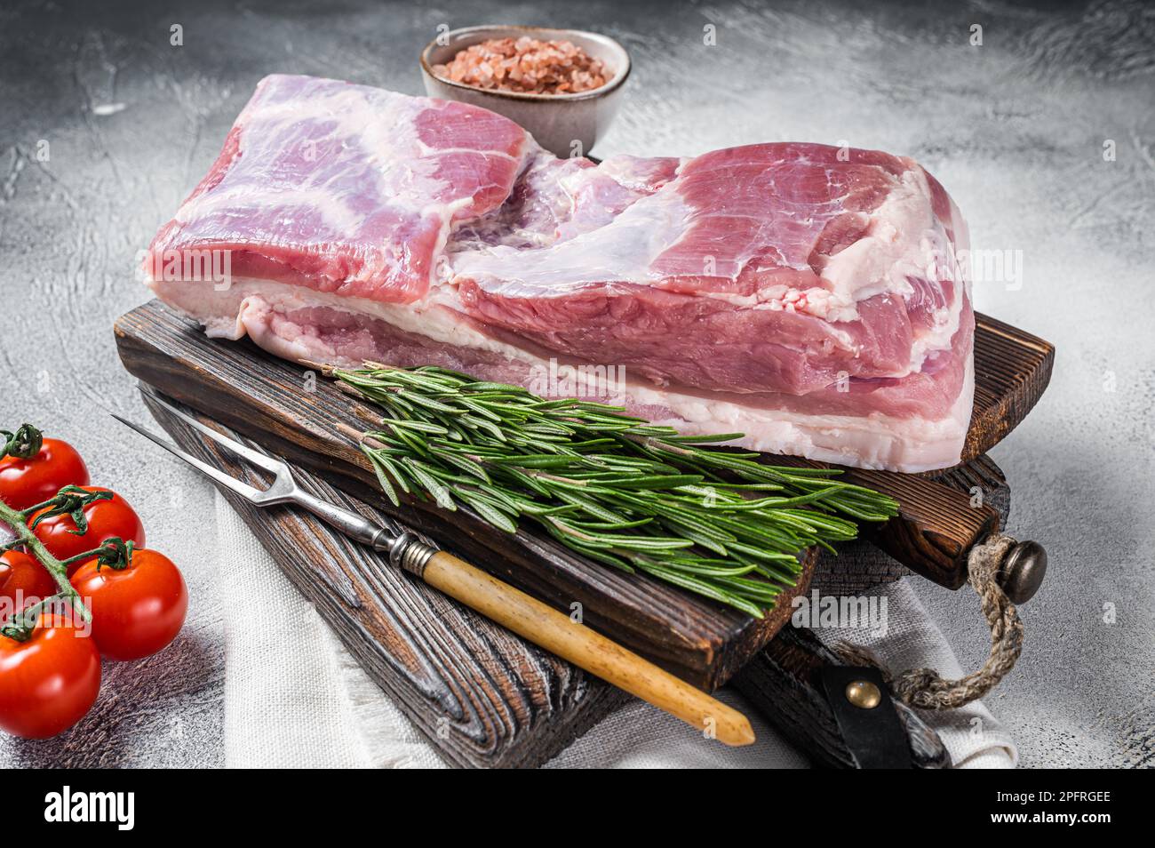 Pork belly block, raw meat with skin on a wooden board with rosemary ...