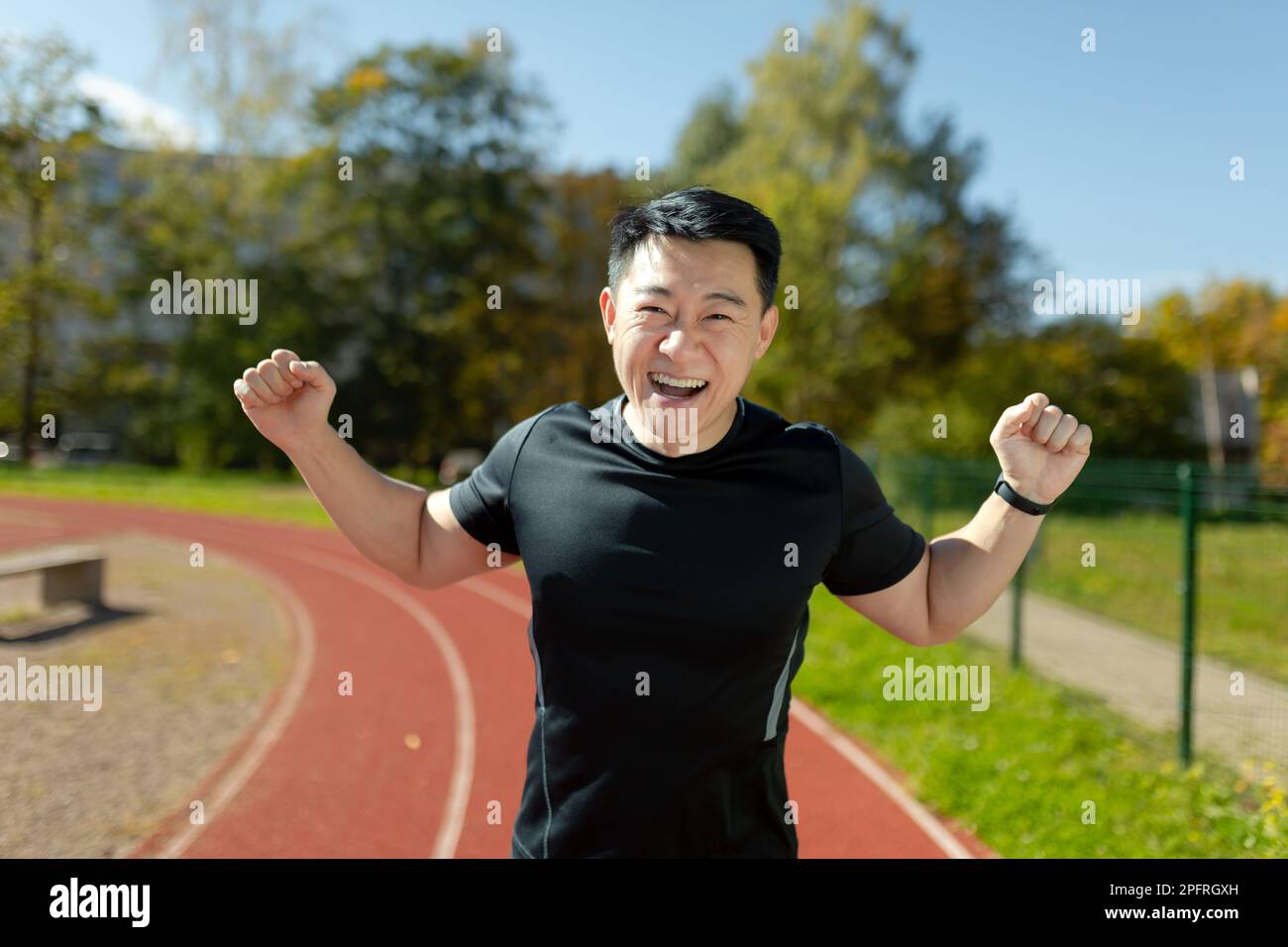 A young Asian man, an athlete, a runner celebrates a victory in a race ...