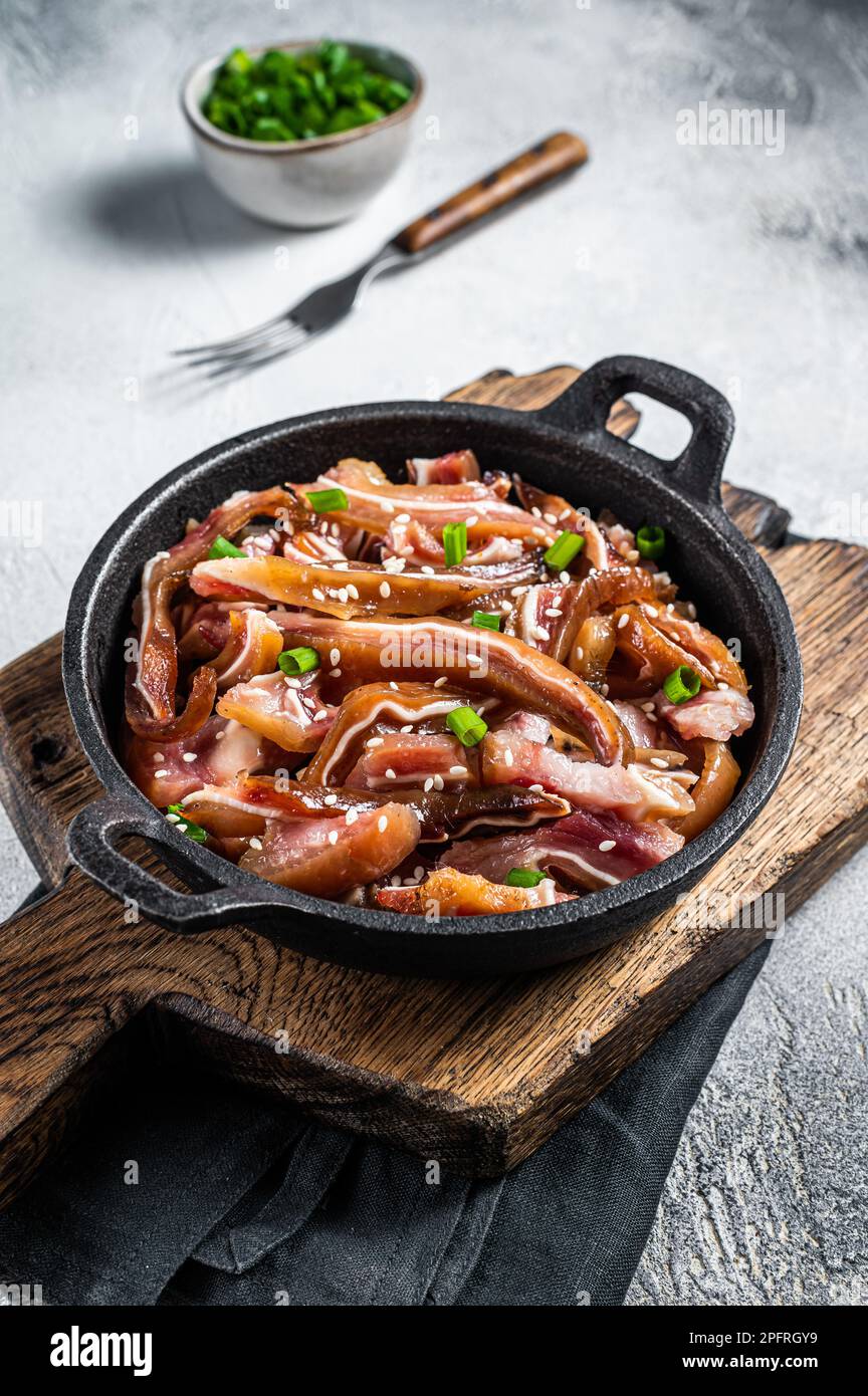 Fried spicy pork pig ears served in a frying pan. white background. Top ...