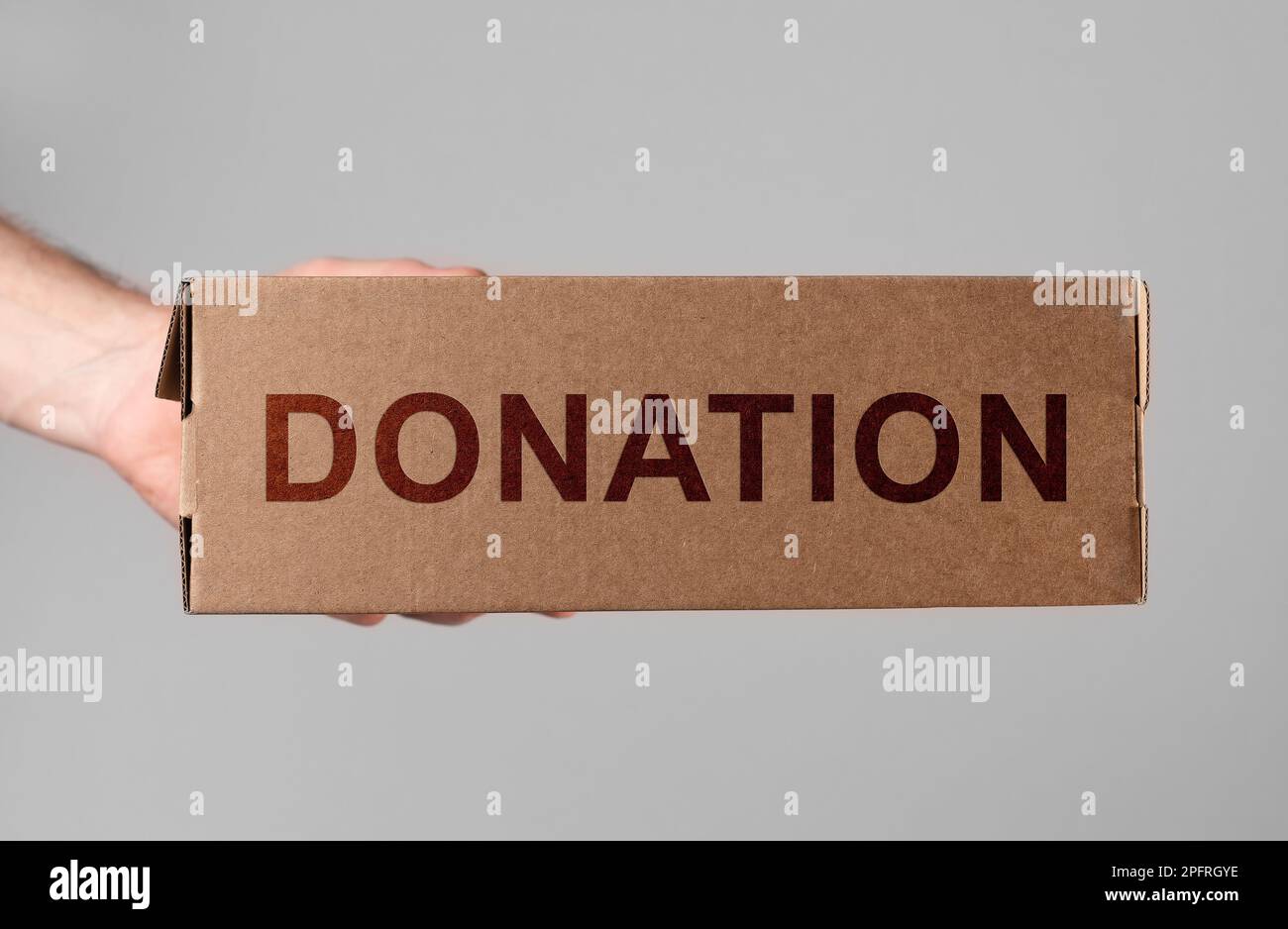 Donation box in hand. Volunteer donating smth, necessities for needy ...