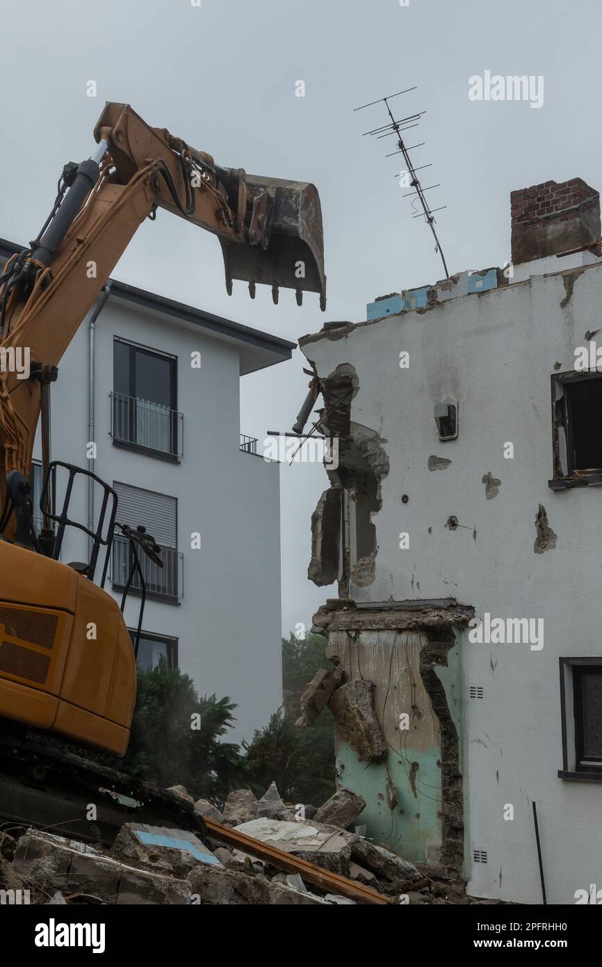 Demolition of a building. An excavator breaks an old house. A new house ...