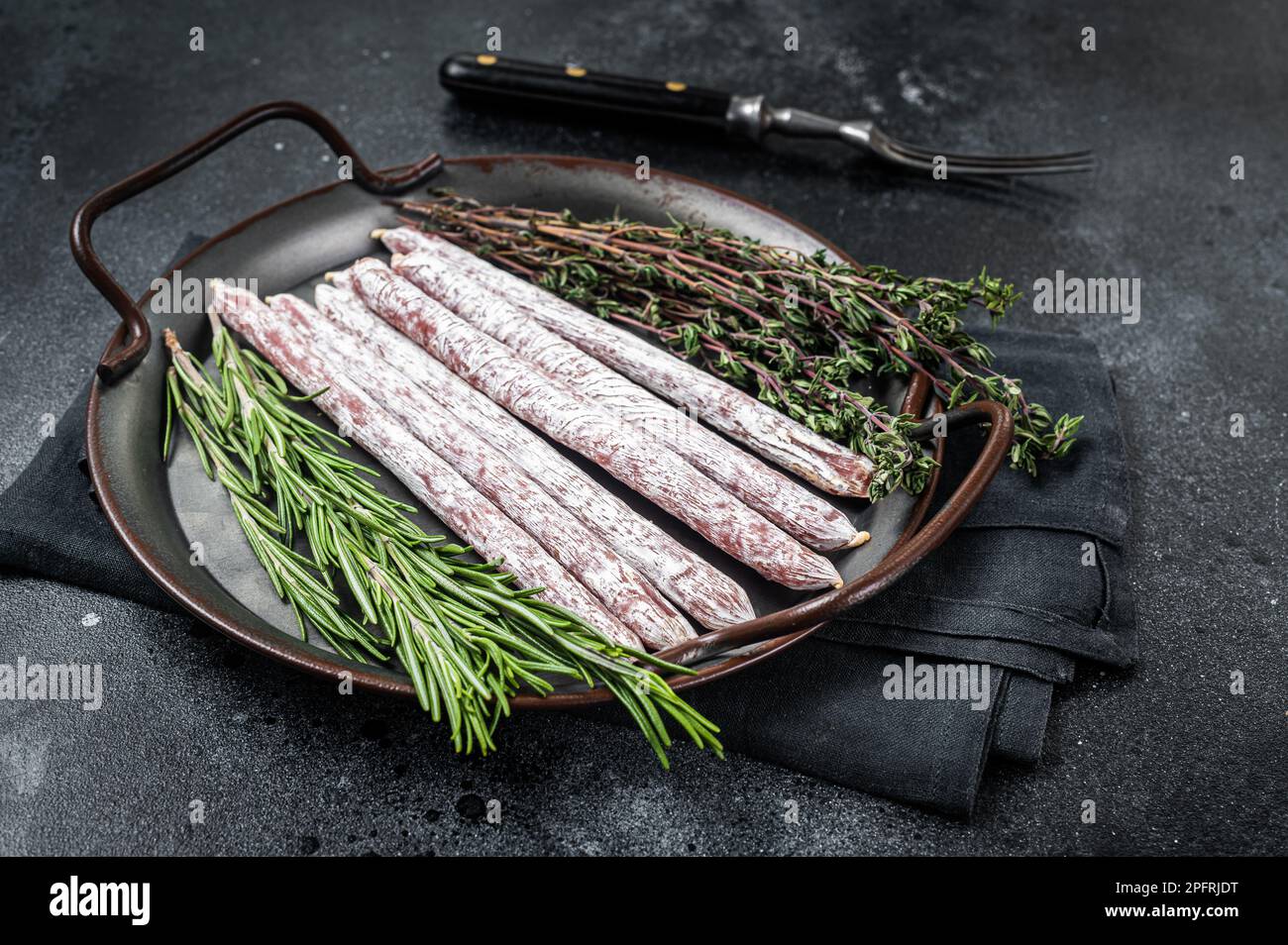 Spanish tapa mini fuet sausage with herbs. Black background. Top view ...
