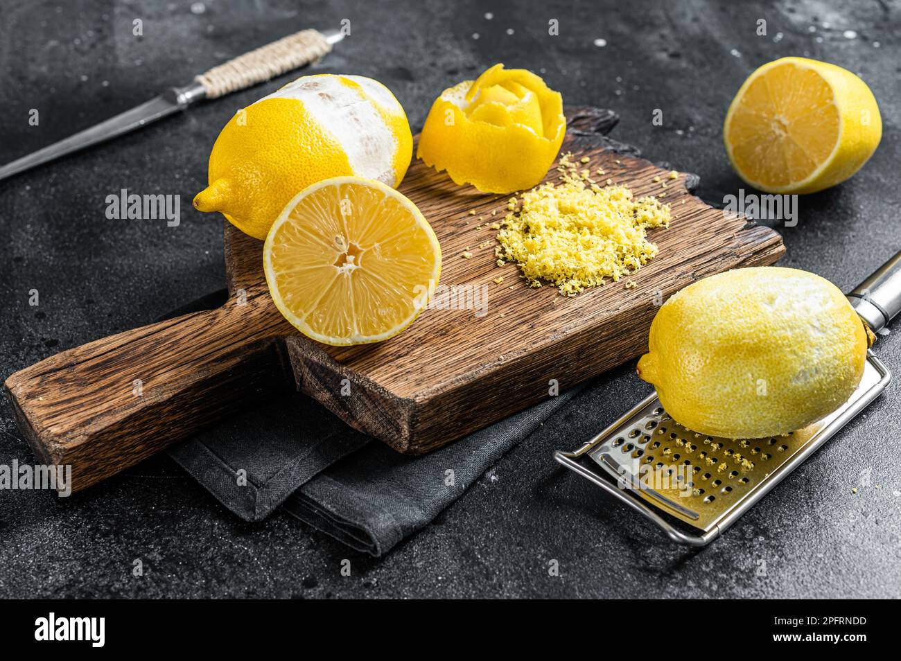 Grated Lemon Zest and spiral peel on wooden board. Black background ...