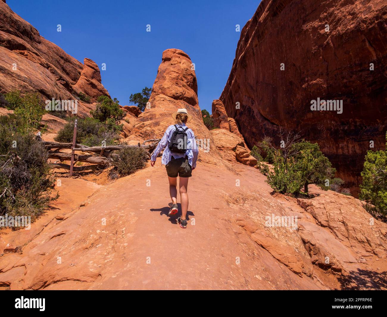An adventurous woman hikes up a rocky path in Arches National Park ...