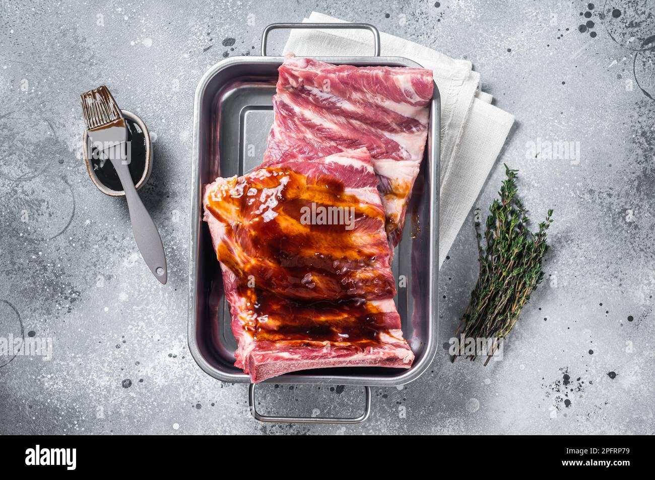 Cooking of Raw pork spare ribs with barbecue sauce. Gray background ...