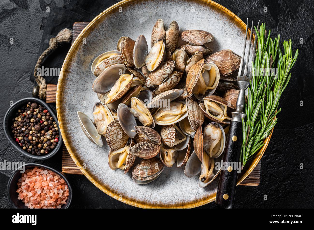 Steamed cooked shells Clams vongole in a plate with herbs. Black ...