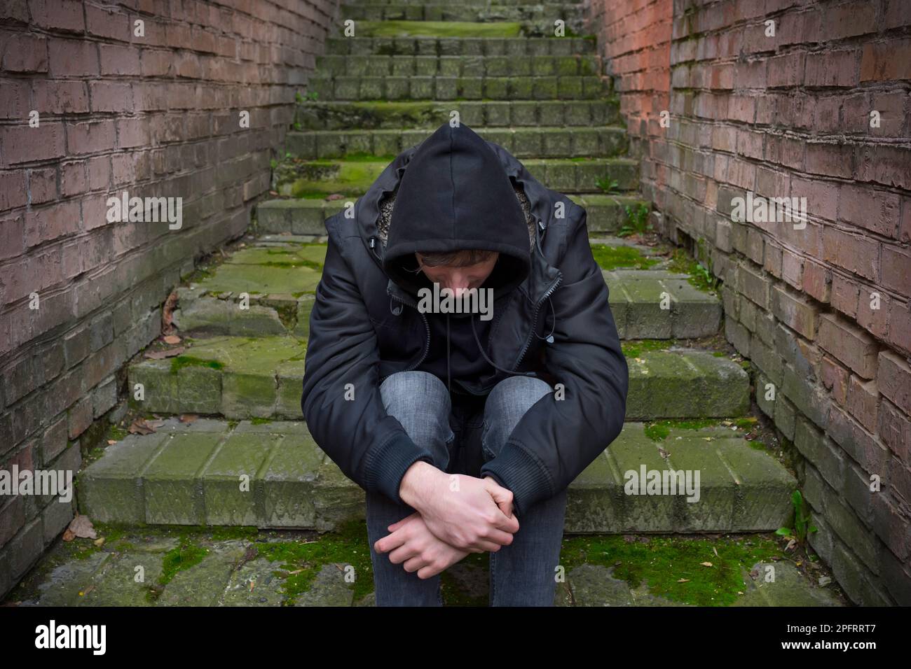 A drug addict man is sitting on the street, experiencing a drug ...