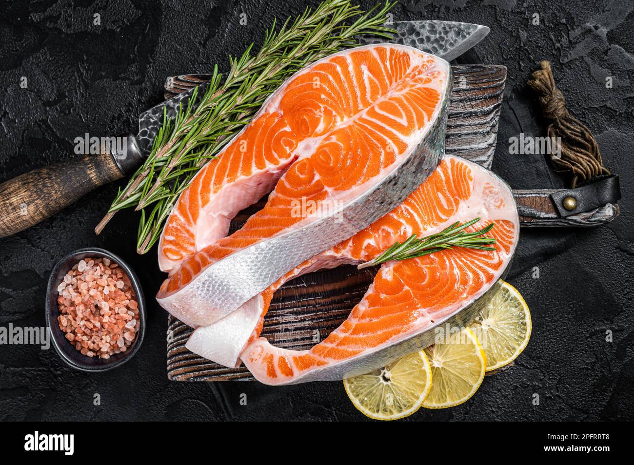 Uncooked Raw Salmon Fish Steaks on butcher board with herbs. Black ...