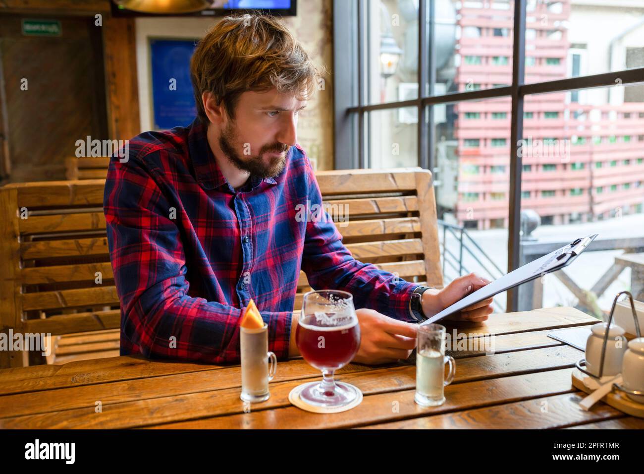 A sad man sits at a table in a pub and drinks strong alcohol ...