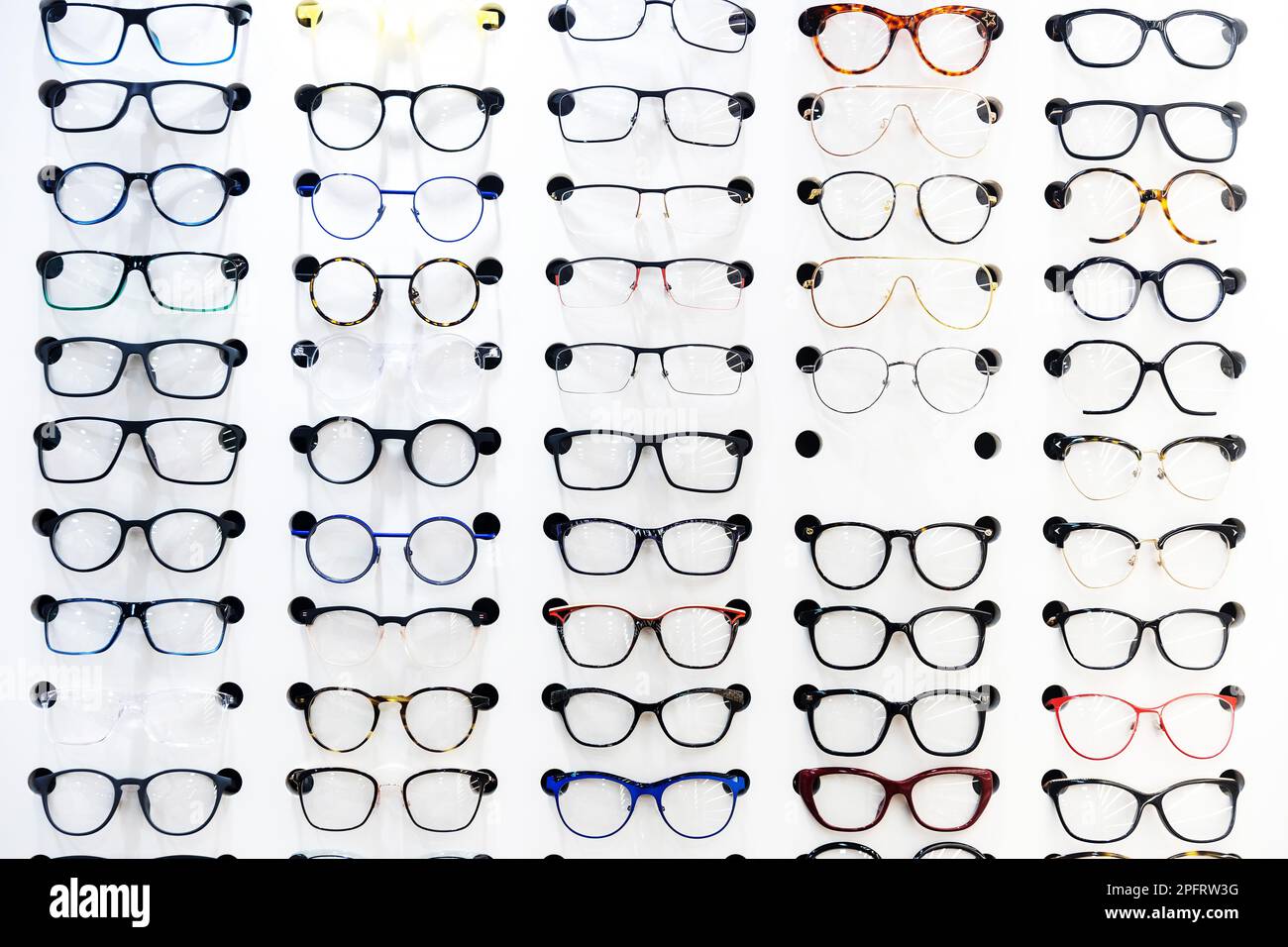 Fashionable corrective eye glasses on shelf in optical store. Many ...