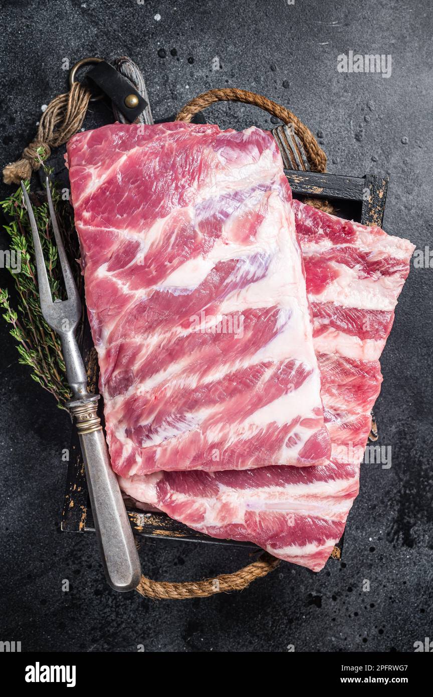 Fresh rack of raw pork spare ribs with herbs. Black background. Top ...